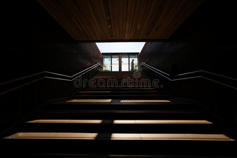 Modern Underground Staircase with Sunlight and Solitary Figure in Glass ...