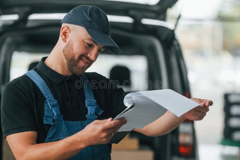 Modern Vehicle. Delivery Man in Uniform is Indoors with Car and with ...