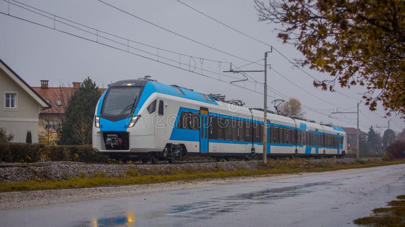 Modern White and Blue Passenger Commuter Train Passing by in Rain ...