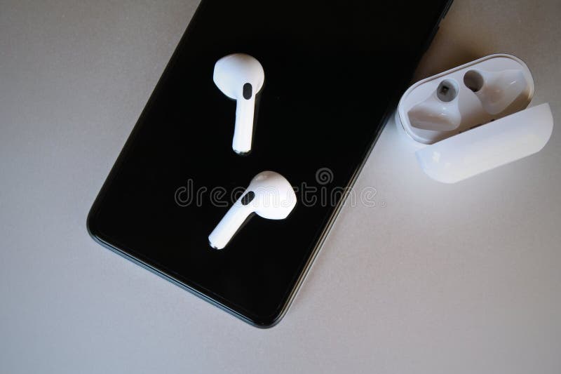 Modern White Wireless Earbuds Lying on a Smartphone Stock Image - Image ...