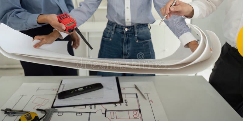 Teamwork and Project Discussion. Professionals Examining Detailed Construction Plans while ...