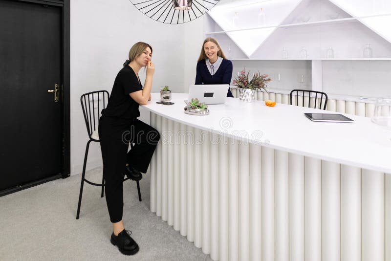 Modern Workspace Featuring Two Women Collaborating at a Stylish White ...