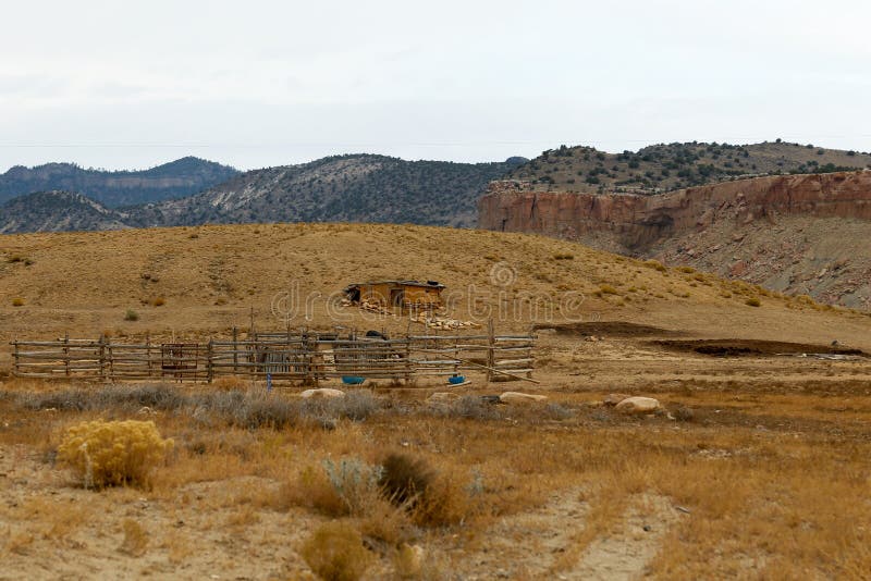 A Rustic Cabin and Fenced Corral Sit on a Desert Landscape Surrounded ...