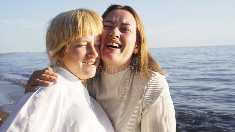 Mom And Daughter Stand On The Seashore At Sunset Hugging Stock Video