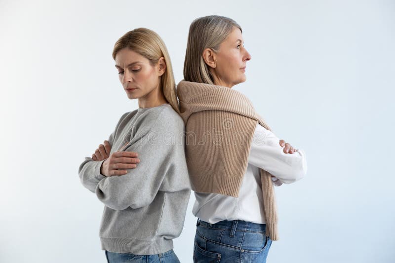 Mom and Daughter Standing Back To Back with Serious Look Stock Photo ...