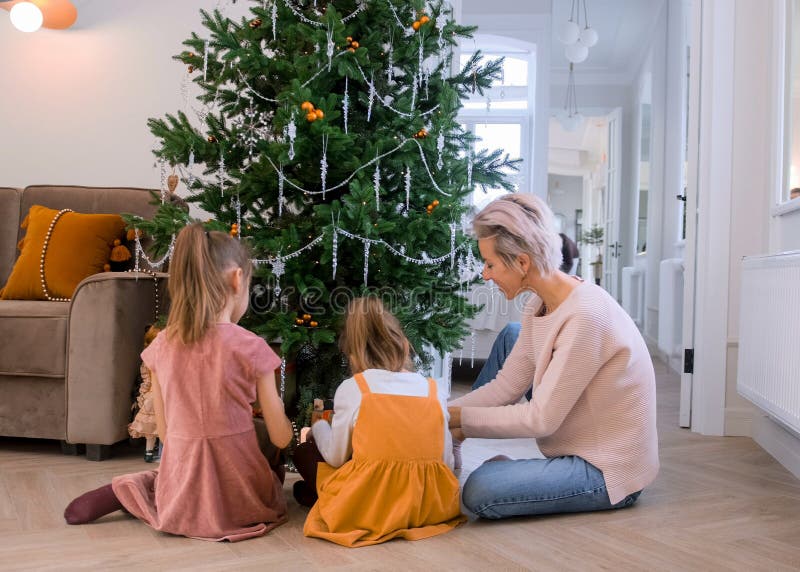 Mom and Daughters Decorate a Christmas Tree Sitting on the Floor in the ...