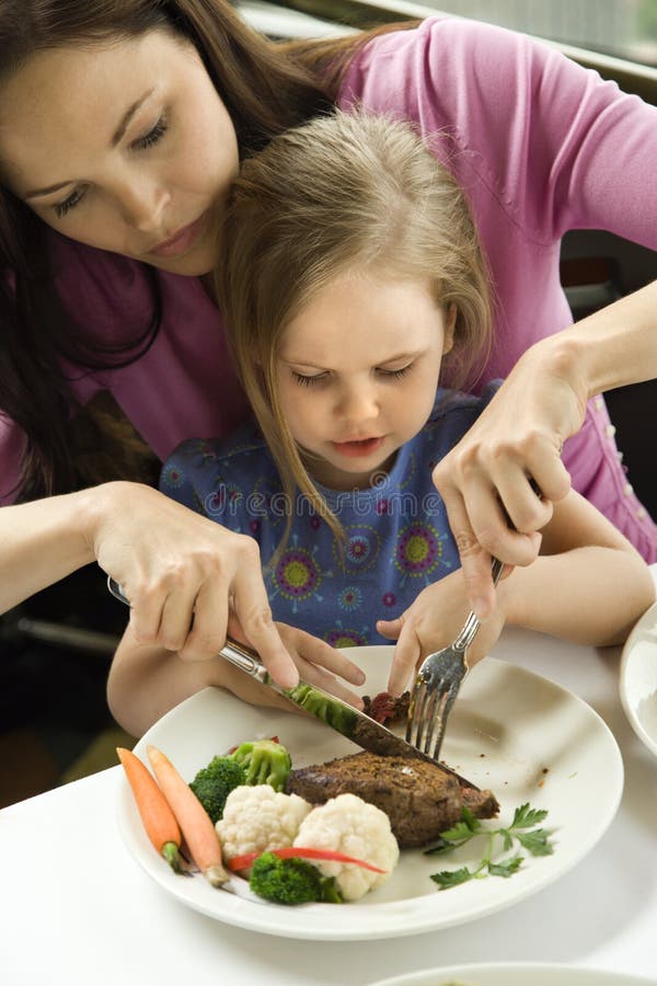 Mom Helping Daughter Cut Food. Stock Image - Image of 070507r0157 ...