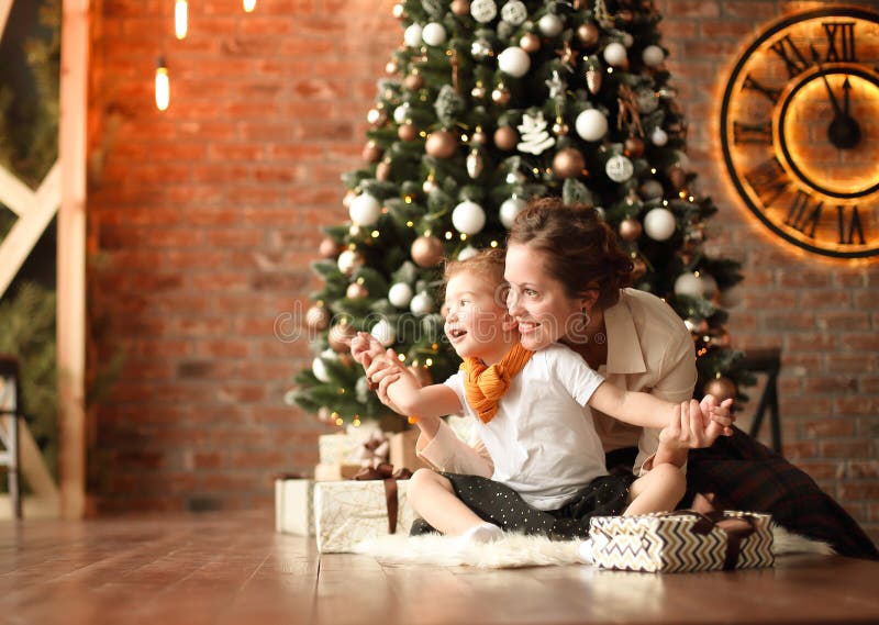 Mom Plays With Her Daughter Sitting Near The Christmas Tree Stock