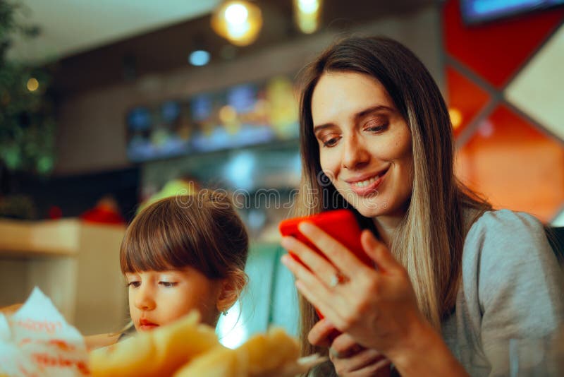 Mother Checking Her Phone at the Table in a Restaurant Stock Image ...