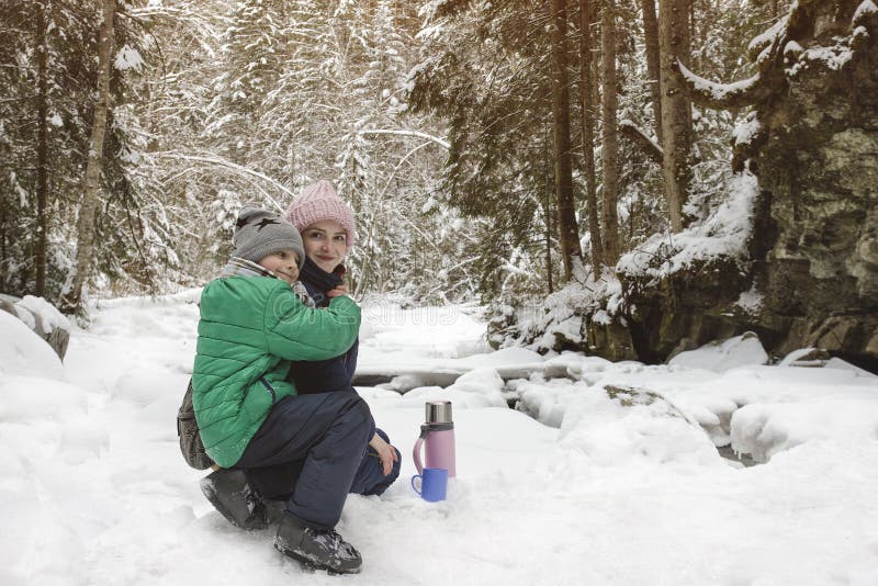 Mom And Son Are Sitting And Hugging Against The Backdrop Of Snow