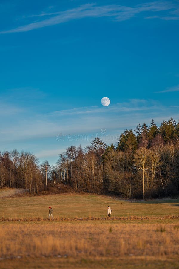 The Moon at Daytime Over People Walking Across a Field.. Stock Photo ...
