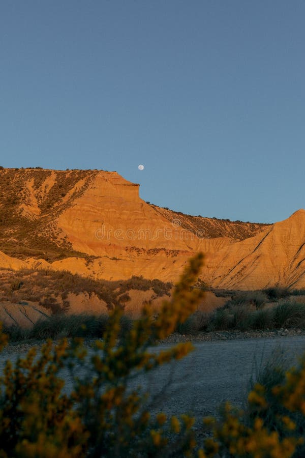 The Moon is Rising in the Distance As it Sets Over a Rocky Cliff Stock ...