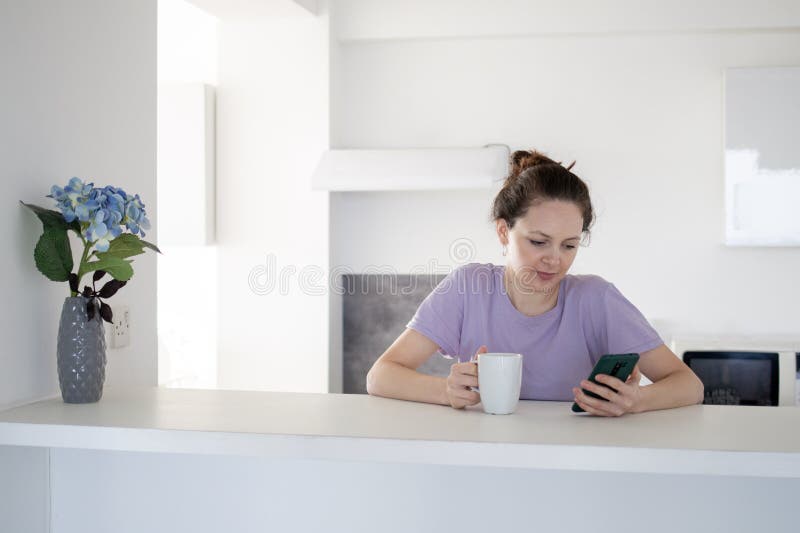 The Morning Routine of a Young Woman Using Her Phone in the Kitchen ...