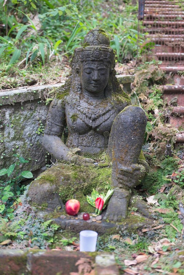 Moss-Covered Stone Statue with Fruit Offerings in Nature Stock Photo ...