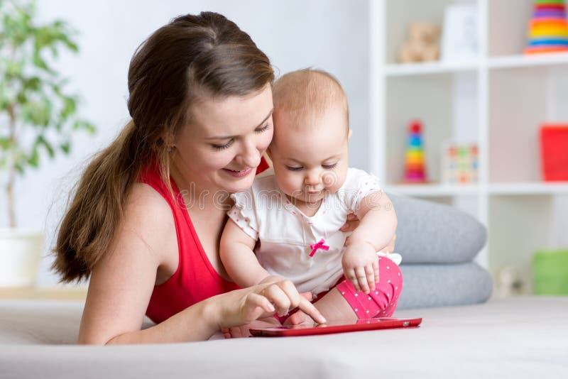 Mother and Baby are Looking To Play Tablet Computer on the Couch at ...