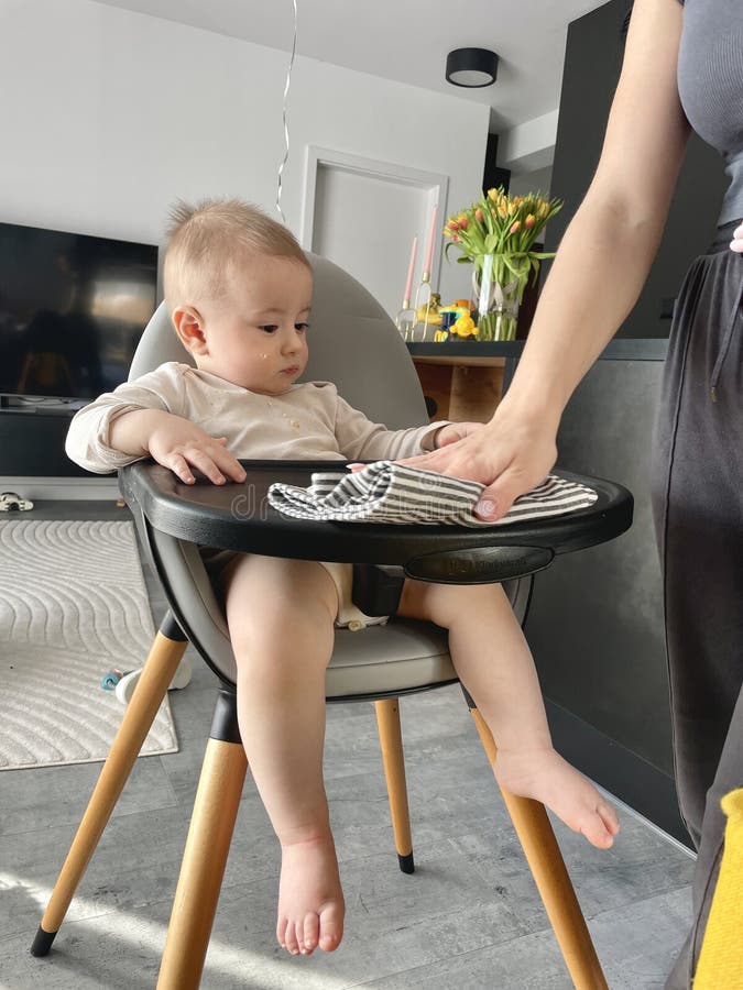 A Mother Cleans the Feeding Table, at Which a Baby Boy is Sitting ...