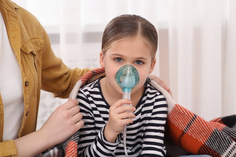 Mother Covering Her Daughter with Plaid while she Using Nebulizer for Inhalation at Home Stock ...