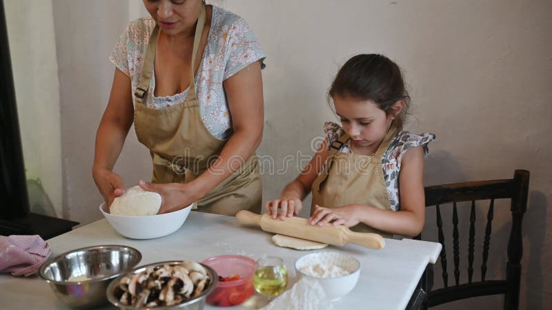 Mother And Daughter Making Pizza Dough Together In The Kitchen