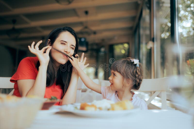 Mother And Daughter Playing Together Having Fun In A Restaurant Stock