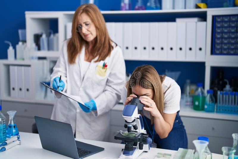 Mother and Daughter Scientists Writing on Document Using Microscope at ...