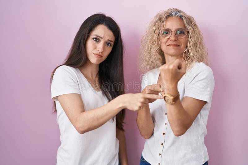 Mother And Daughter Standing Together Over Pink Background Laughing And