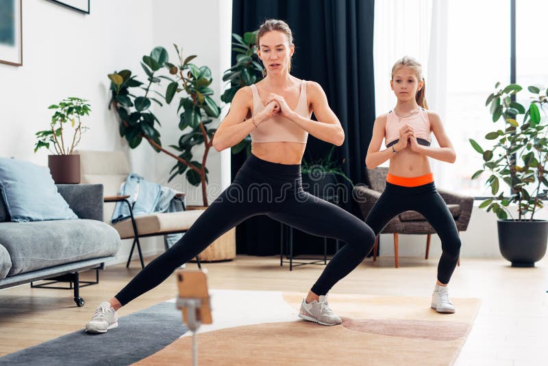 Mother and Daughter Working Out at Home, Doing Leg Stretches, Side To ... Mother and Daughter Working Out at Home, Doing Leg Stretches, Side To ...