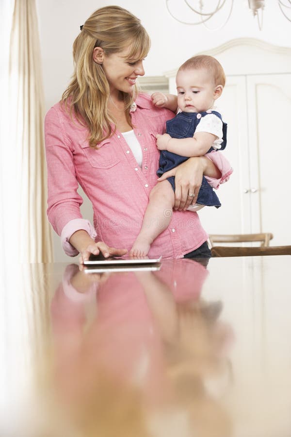 Mother Holding Baby Daughter Whilst Using Digital Tablet Stock Photo ...