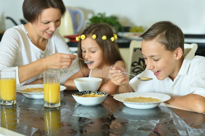 Mother with Kids Eating at Table Stock Photo - Image of smile, cheerful ...