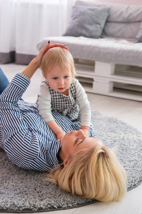 Mother Lying on the Floor Holding Her Cute Baby Stock Photo - Image of ...
