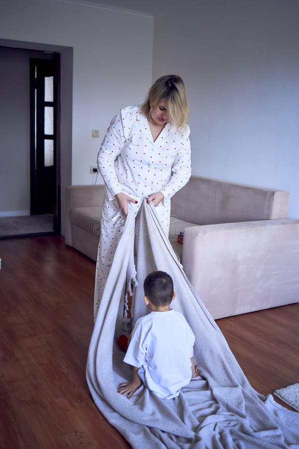 A Mother Plays and Drags Her Little Son on a Sheet Around the Room ...