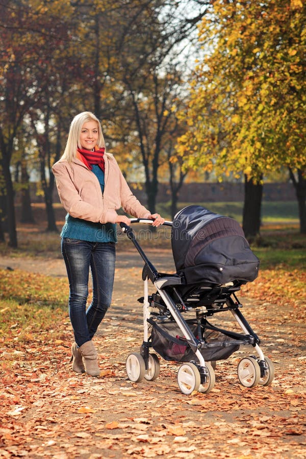 Mother Pushing a Baby Stroller in a Park in Autumn Stock Photo - Image ...