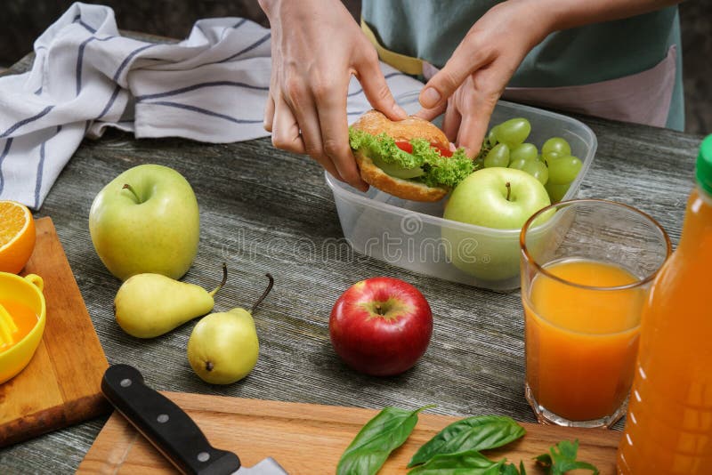 Mother Putting Food for Schoolchild in Lunch Box on Table Stock Photo ...