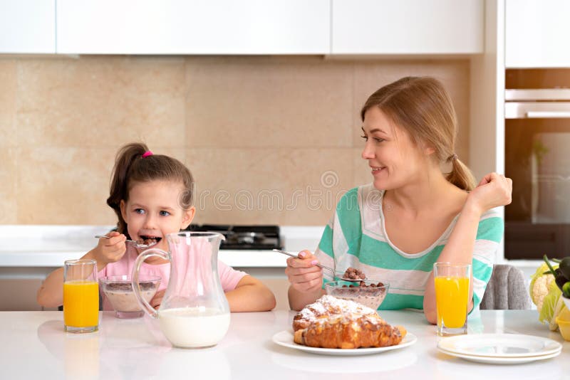 Mother Having Breakfast with Her Daughter at a Table in Kitchen, Happy ...