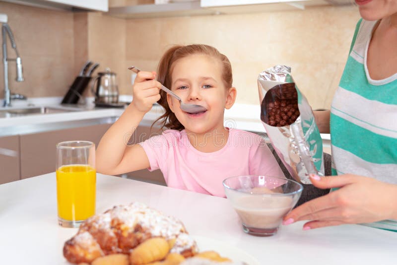 Mother Having Breakfast with Her Daughter at a Table in Kitchen, Happy ...