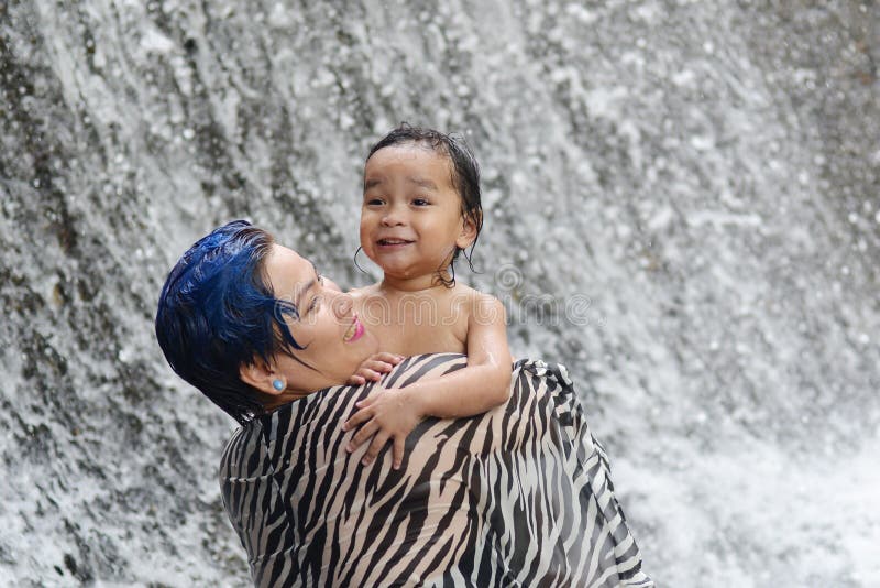 Mother and Son Sitting on Rock by Waterfall Stock Photo - Image of ...