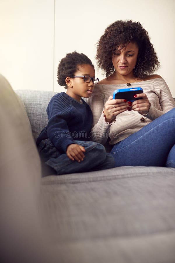 Mother and Son Sitting on Sofa at Home Playing Computer Game Together ...