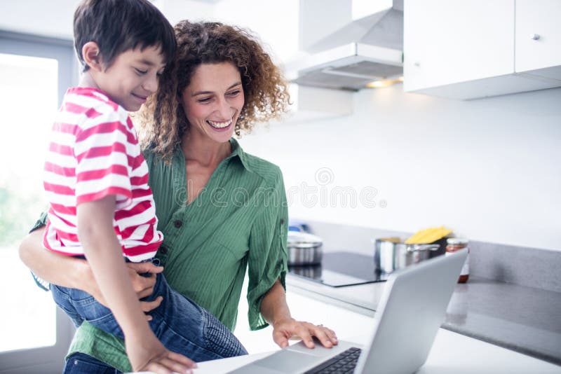 Mother and Son Using Laptop in Kitchen Stock Photo - Image of ...