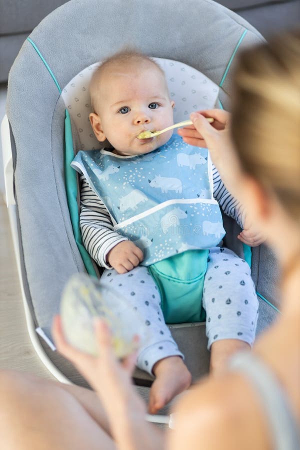 Mother Spoon Feeding Her Baby Boy Infant Child in Baby Chair with Fruit ... Mother Spoon Feeding Her Baby Boy Infant Child in Baby Chair with Fruit ...