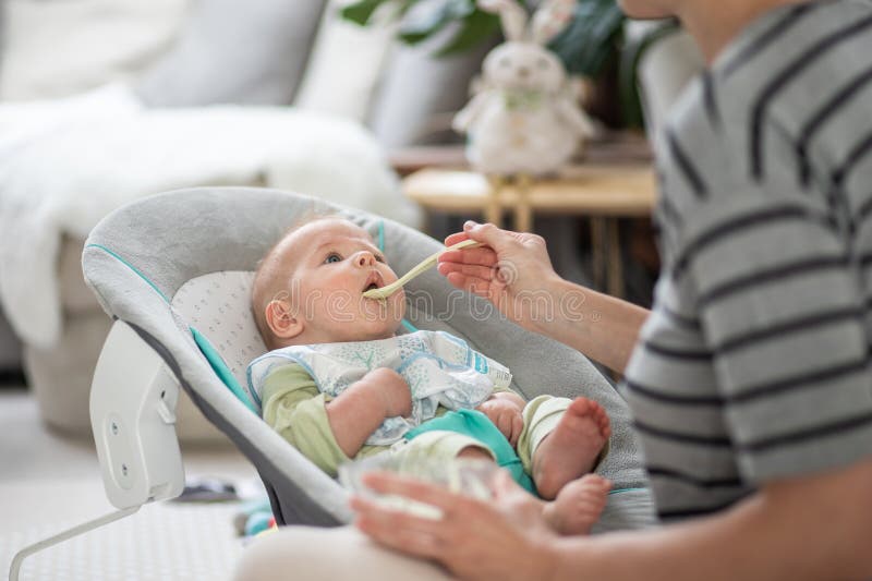 Mother Spoon Feeding Her Baby Boy Infant Child in Baby Chair with Fruit ... Mother Spoon Feeding Her Baby Boy Infant Child in Baby Chair with Fruit ...