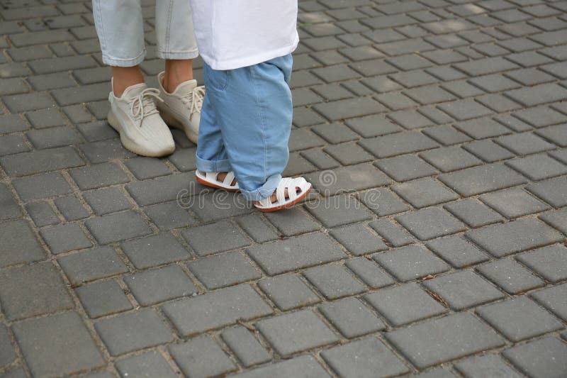 Mother Supporting Daughter while she Learning To Walk Outdoors, Closeup ...