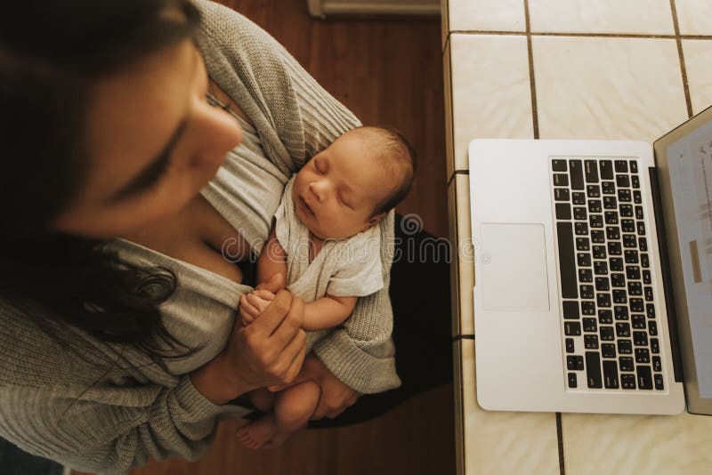 Mother Using a Computer and Holding Her Baby Stock Image - Image of ...