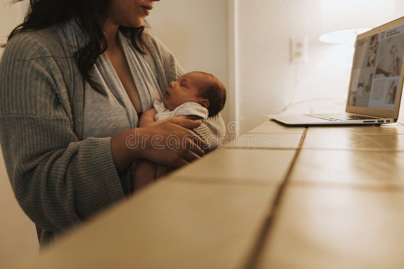 Mother Using a Computer and Holding Her Baby Stock Image - Image of ...