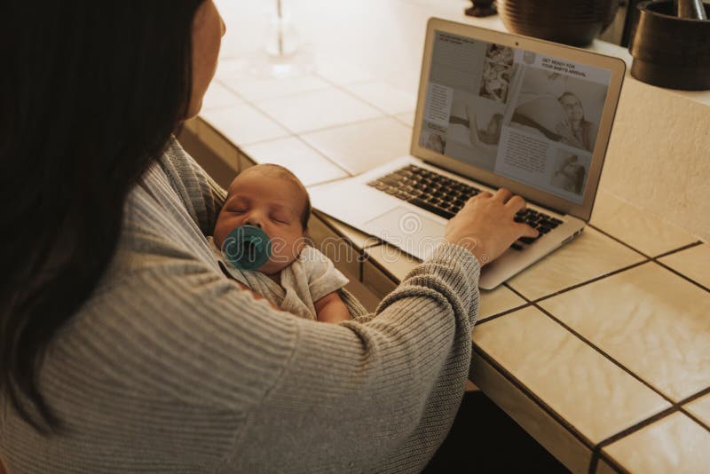 Mother Using a Computer and Holding Her Baby Stock Image - Image of ...