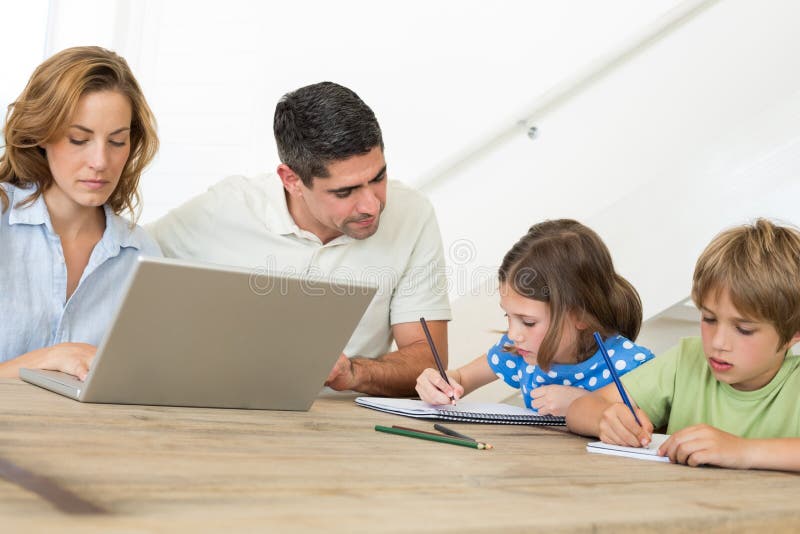 Mother Using Laptop while Father Assisting Children in Coloring Stock ...