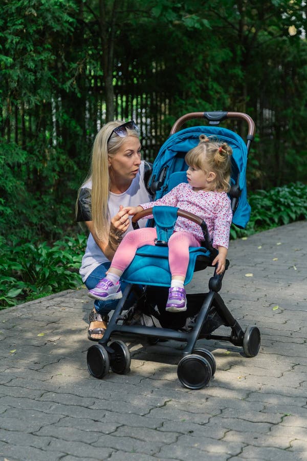 Mother Walking while Pushing a Stroller in the Park Stock Photo - Image ...