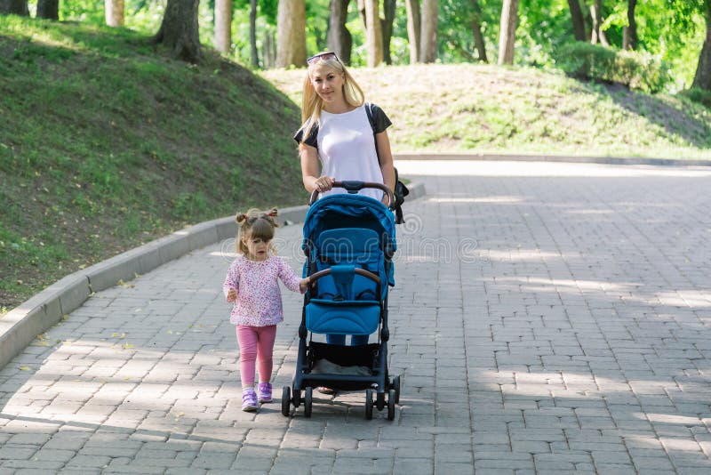 Mother Walking while Pushing a Stroller in the Park Stock Photo - Image ...