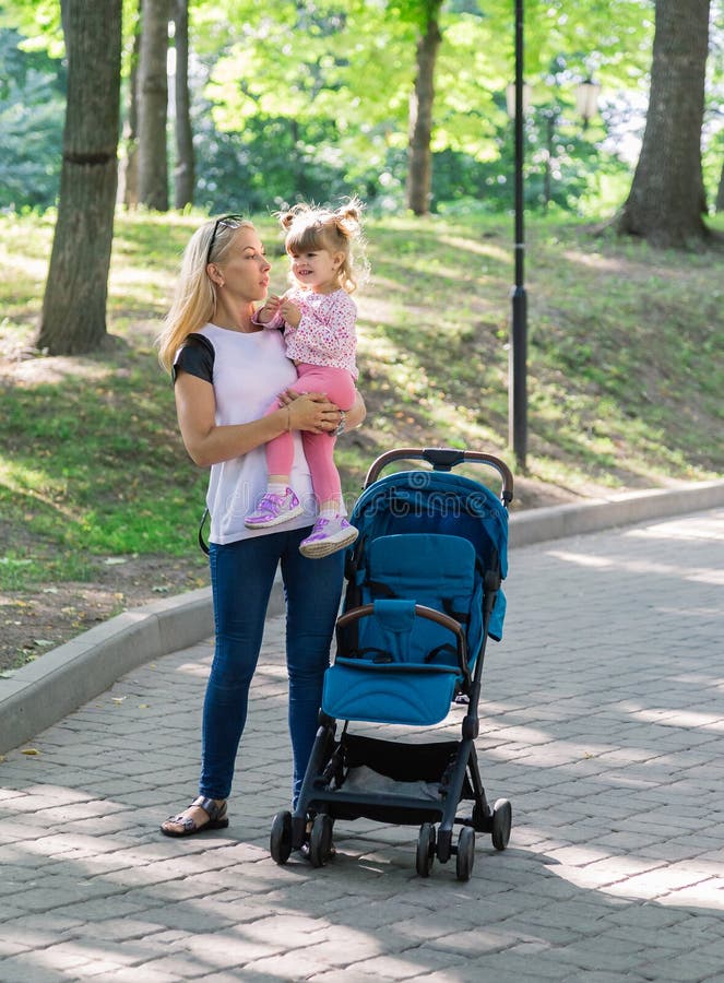Mother Walking while Pushing a Stroller in the Park Stock Photo - Image ...