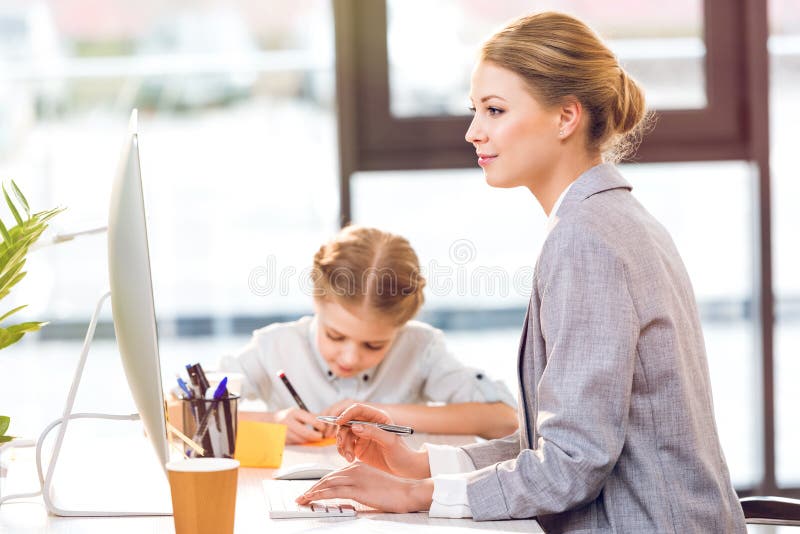 Mother Working with Computer while Her Daughter Drawing in Business ...