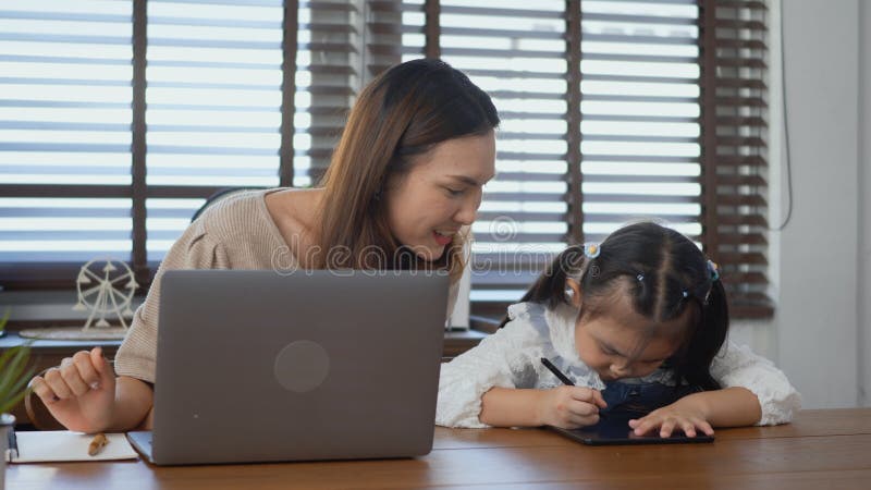 Mother Working with Laptop Computer at Home and Help Daughter Doing ...