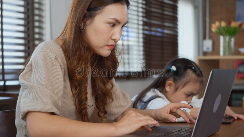 Mother Working with Laptop Computer at Home and Help Daughter Doing ...